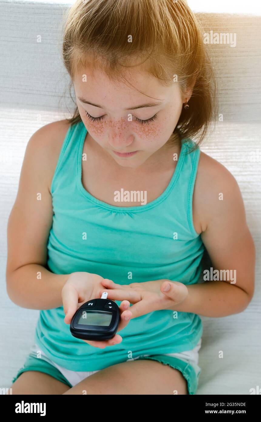 Little girl with diabetes measuring glucose levels in blood at home ...