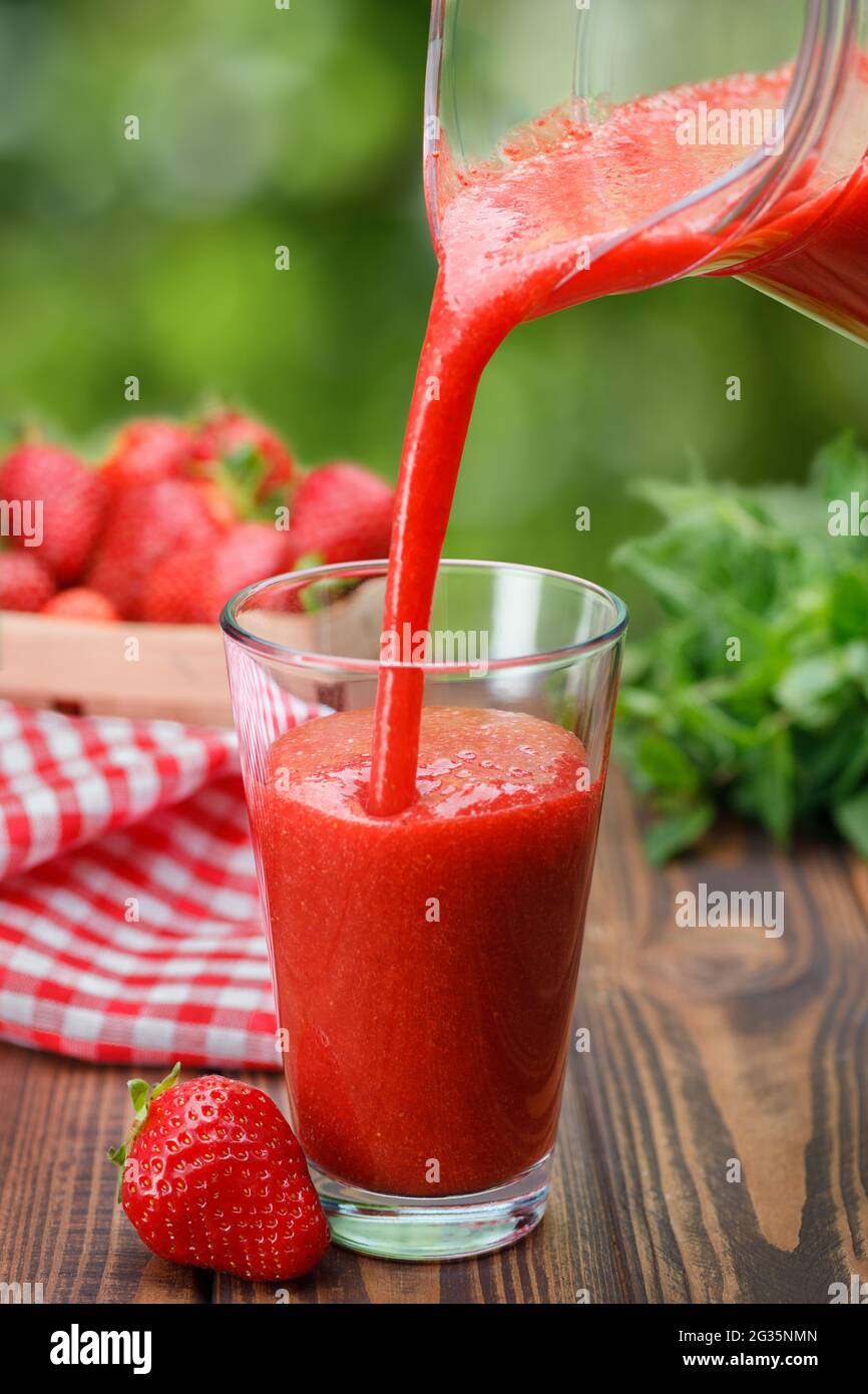 strawberry smoothie pouring from jug into glass Stock Photo - Alamy