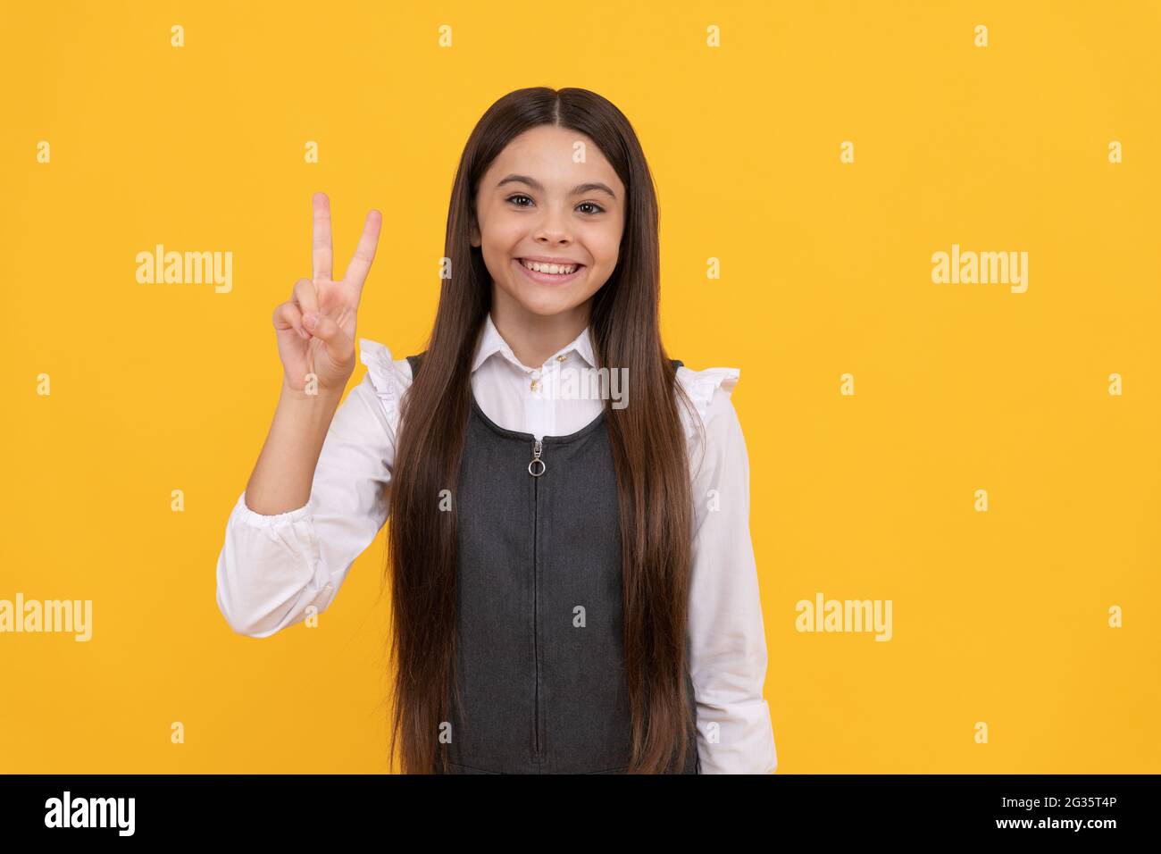 Happy girl child smile showing V sign hand gesture yellow background ...