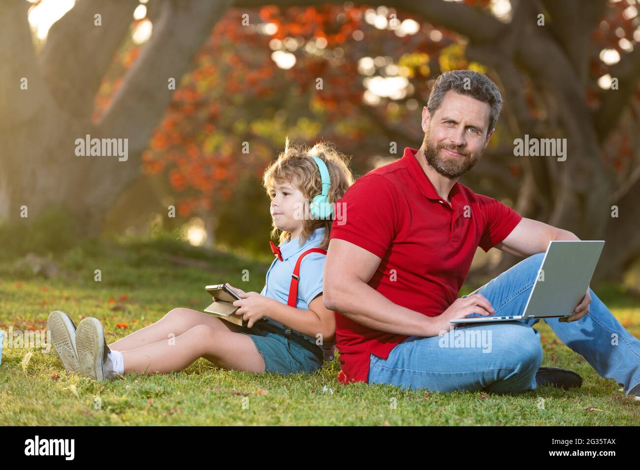 father and son use modern communication technology in park. family blog ...