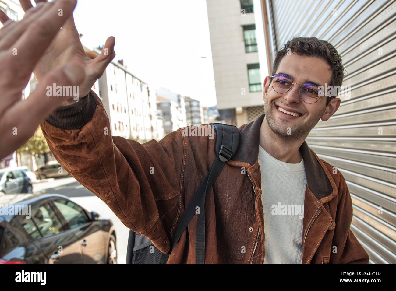 smiling young man waving on the street Stock Photo - Alamy