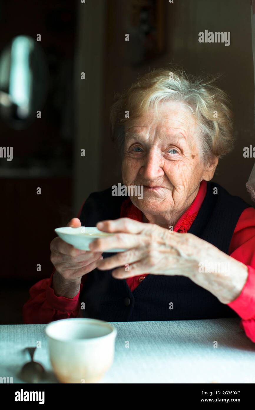 An old woman sits drinking tea, a portrait of grandmother in her home ...