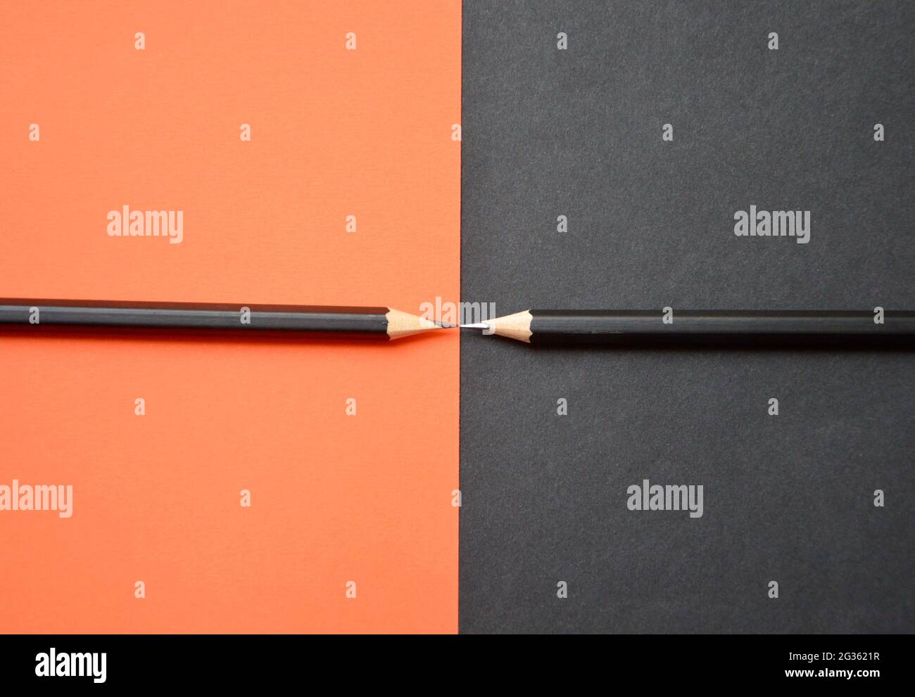 Overhead photo of two black pens pointing toward each other on ...