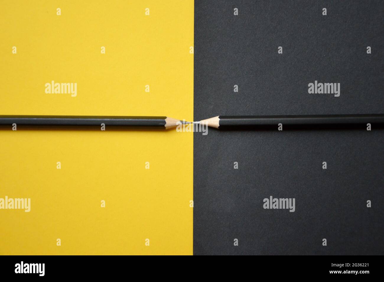 Overhead photo of two black pens pointing toward each other on ...