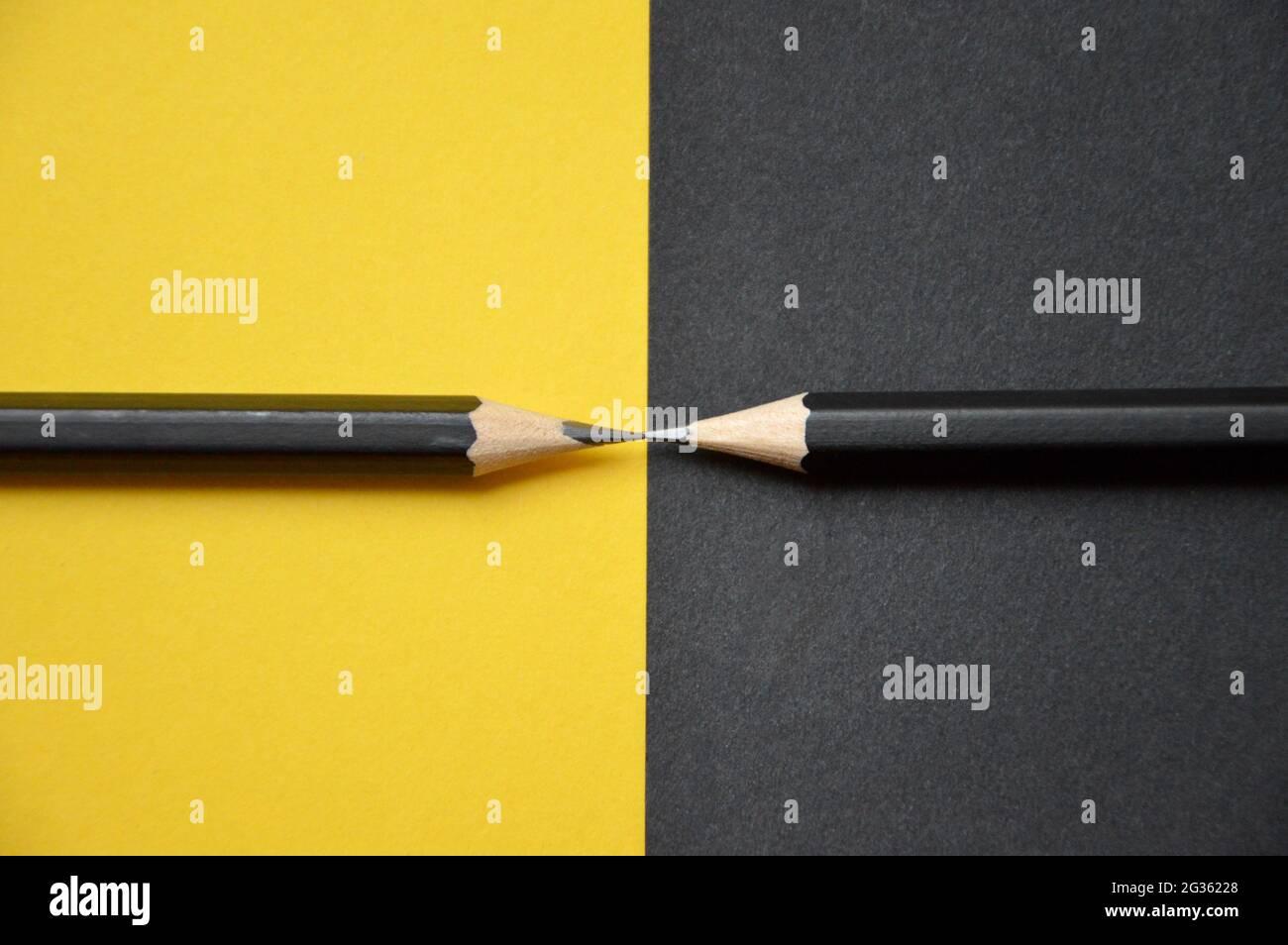 Overhead photo of two black pens pointing toward each other on ...
