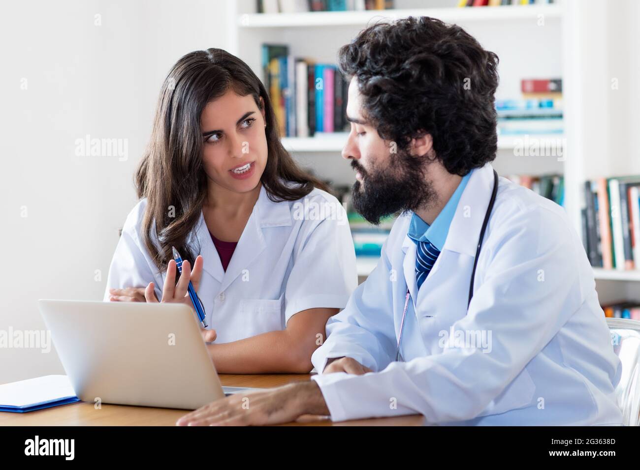 Young arabic female doctor talking with male doctor about patient at ...