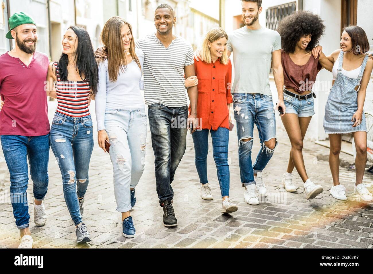 Multiracial millennial friends walking and talking in city center ...