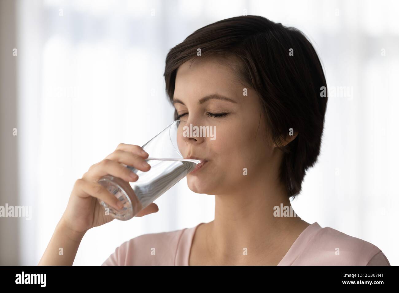 Head shot beautiful dehydrated young woman drinking pure mineral water ...