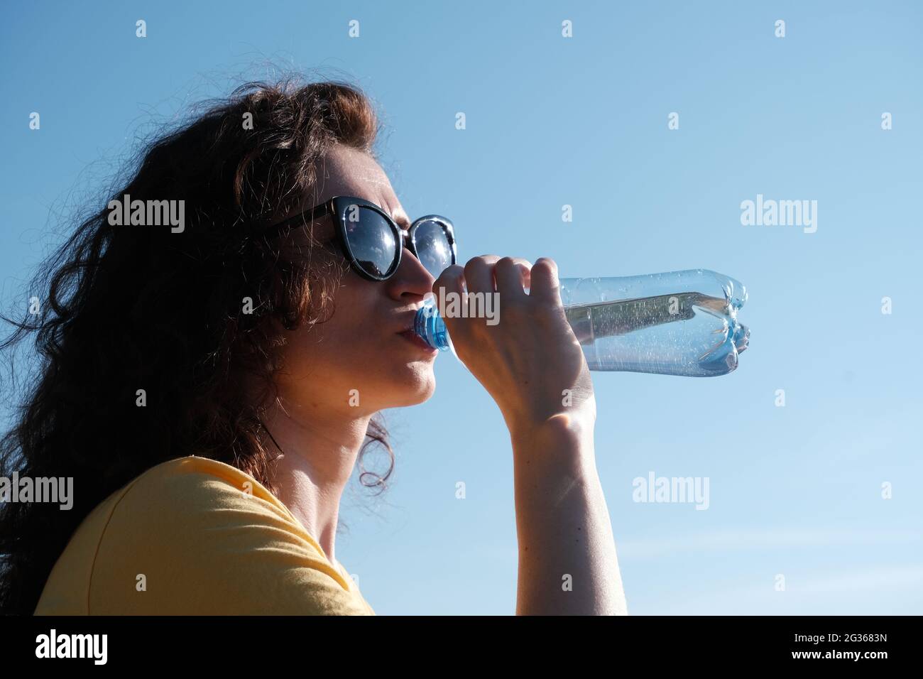 Girl with glasses drinks water from a bottle in hot weather Stock Photo ...