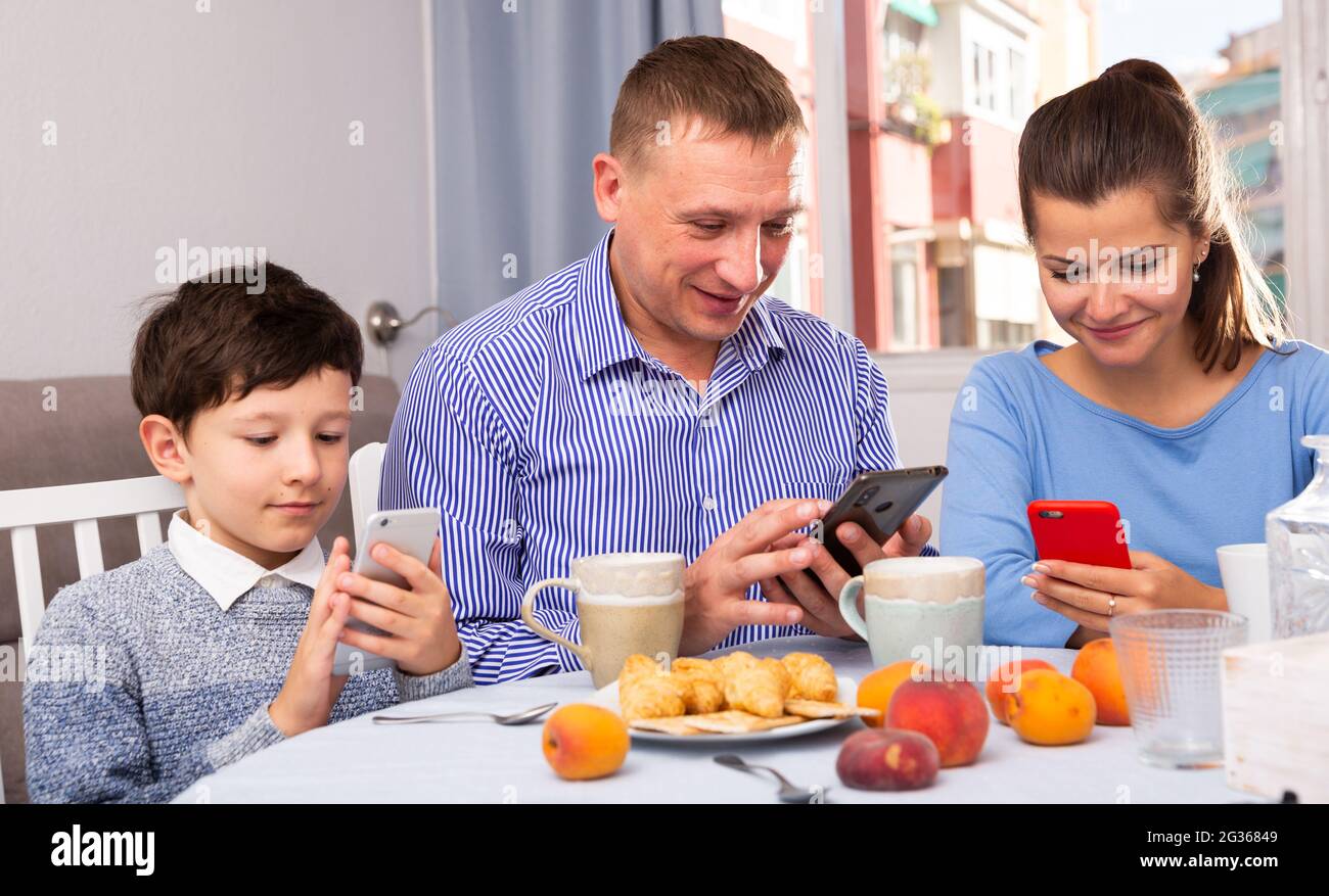 Boy and his parents using phones Stock Photo - Alamy
