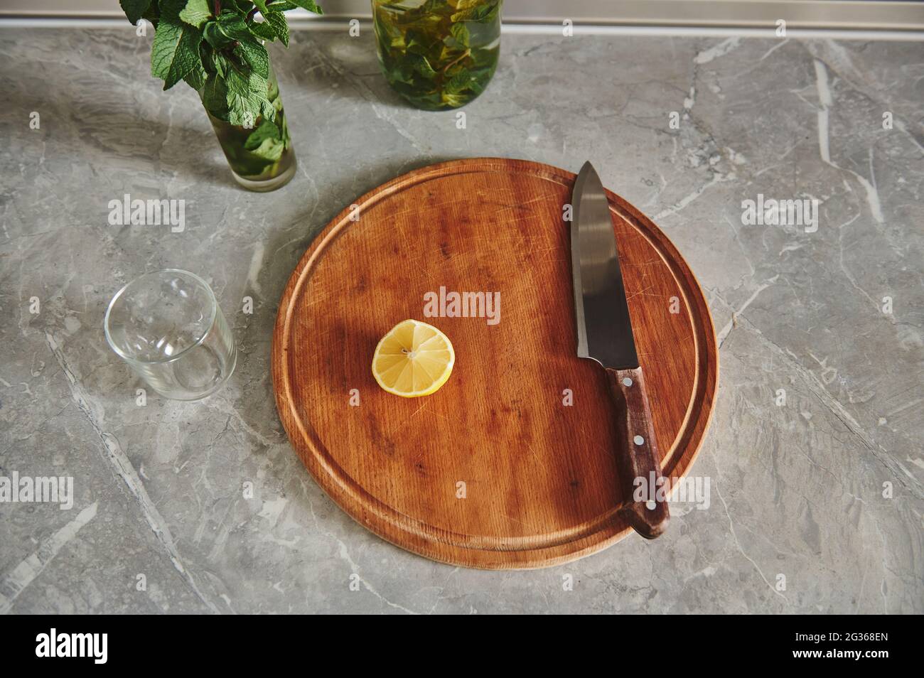 Flat lay composition with a knife and cut lemon in half on round wooden ...