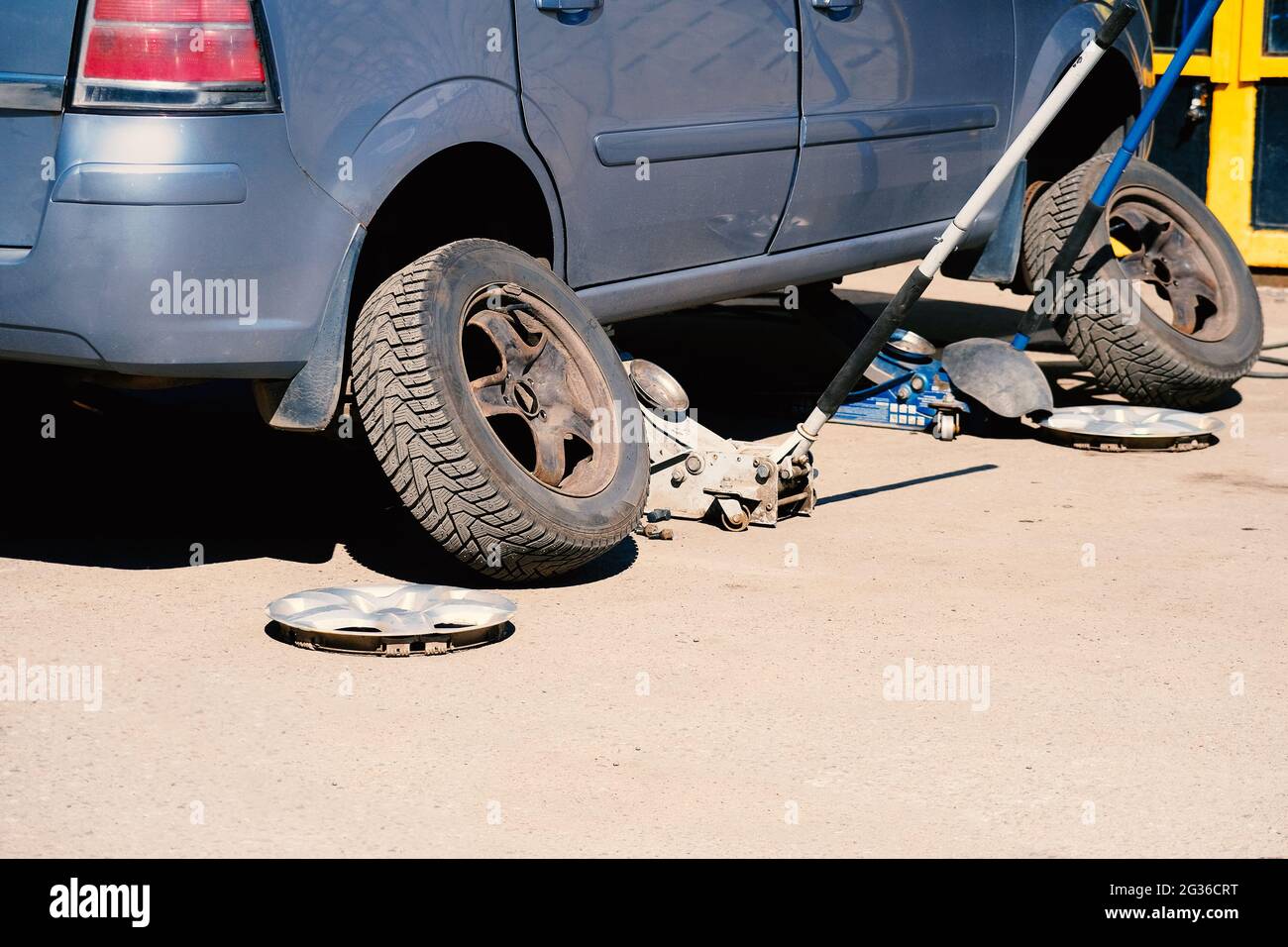 car mechanic screwing or unscrewing car wheel of lifted automobile by ...