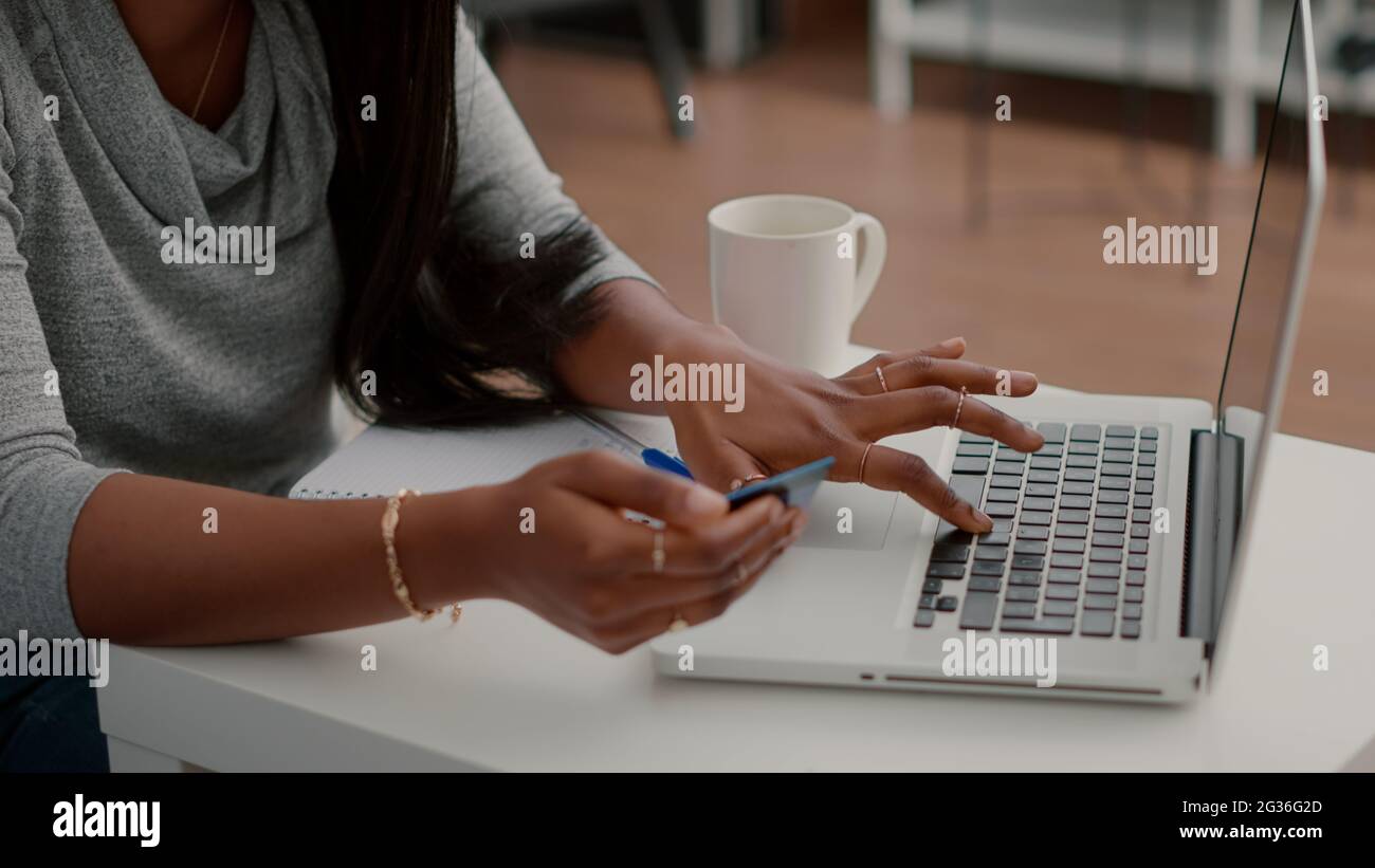 Black student with dark skin using credit card doing shopping sitting ...