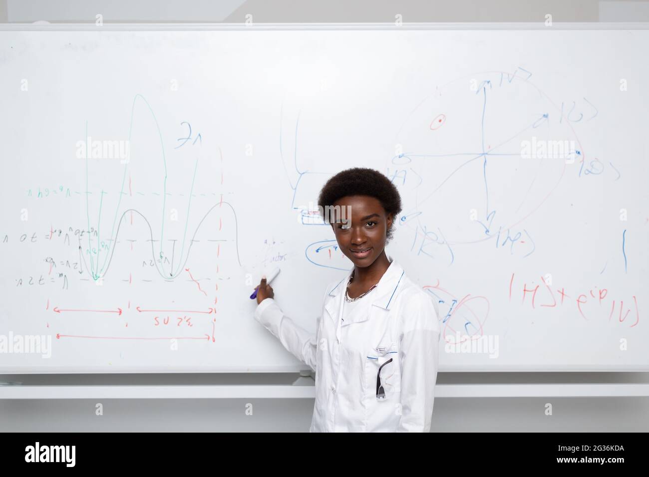 African American woman math teacher writing on blackboard with marker ...
