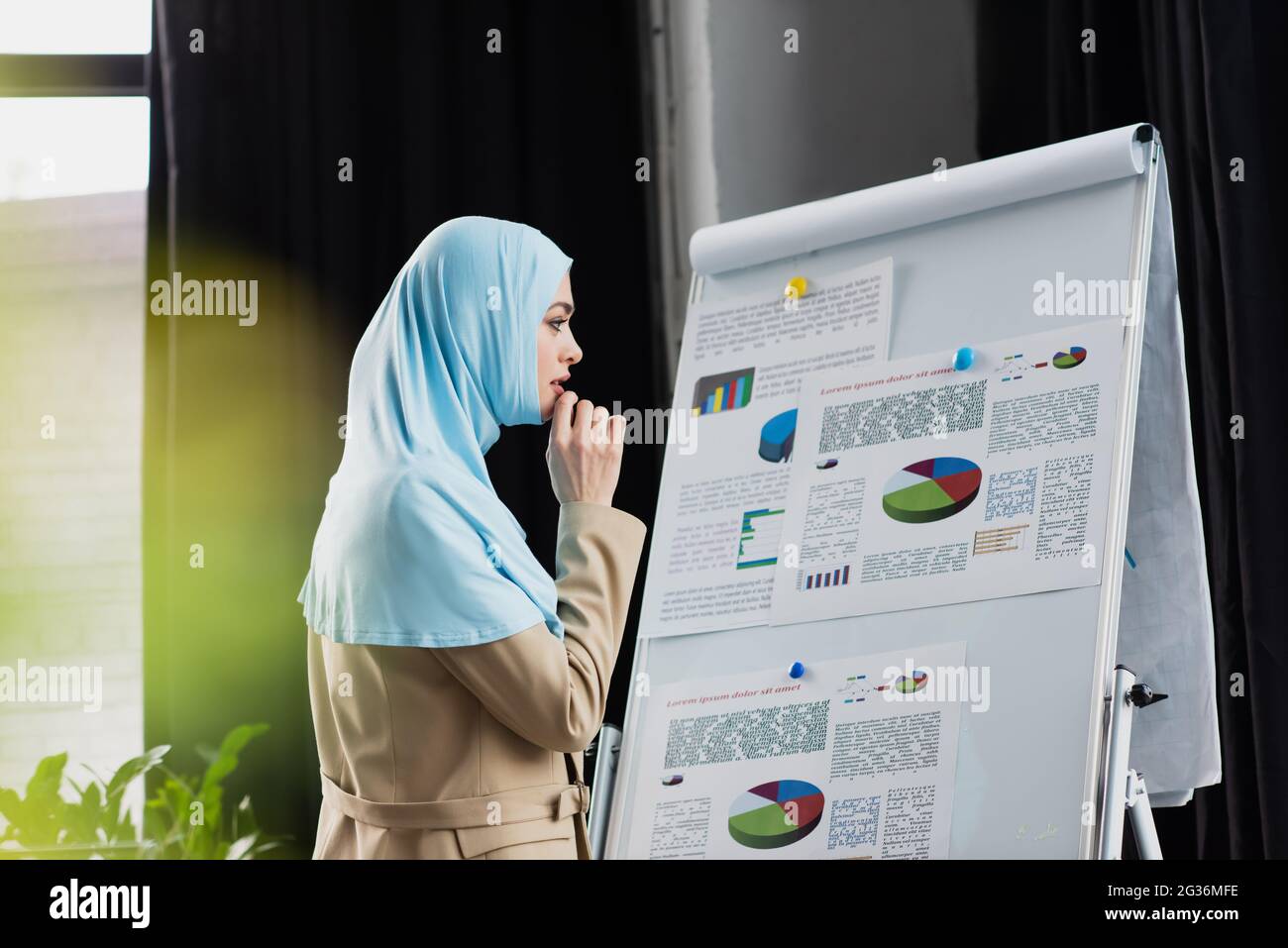 muslim businesswoman looking at flip chart with infographics in office ...