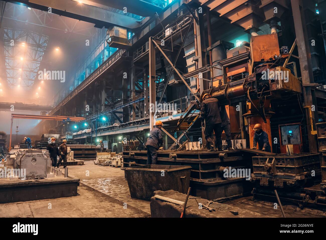 Workers work with molds for smelting iron at steel mill in factory ...