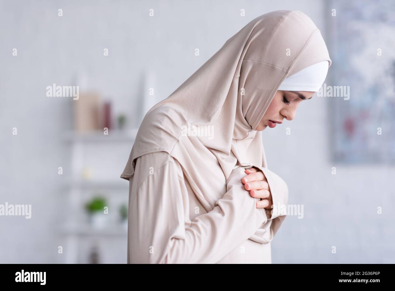 young muslim woman holding hands on chest while praying with closed ...