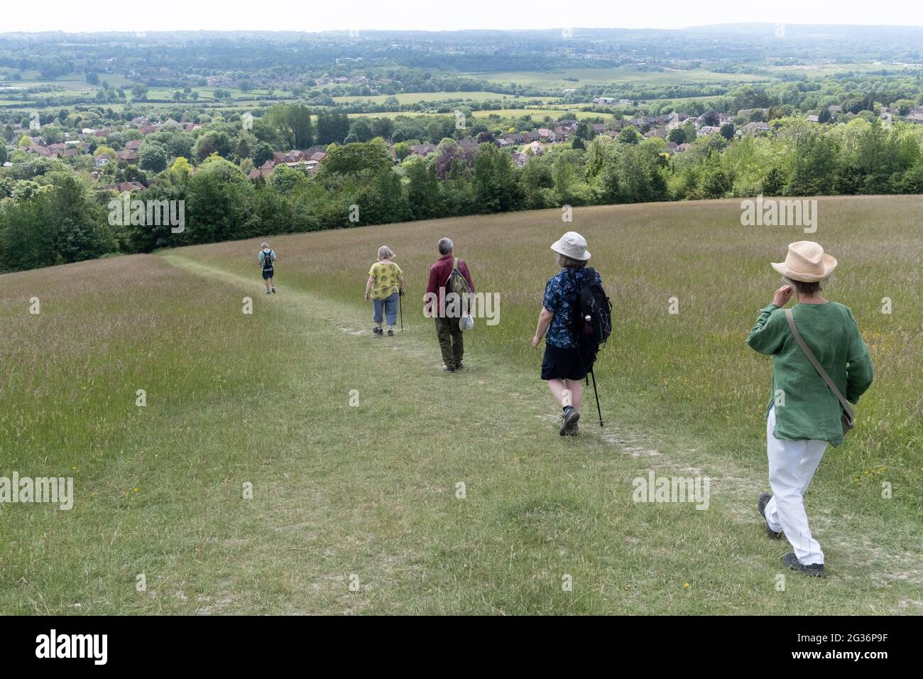 A group of walking friends on a public footpath, descend in single-file ...