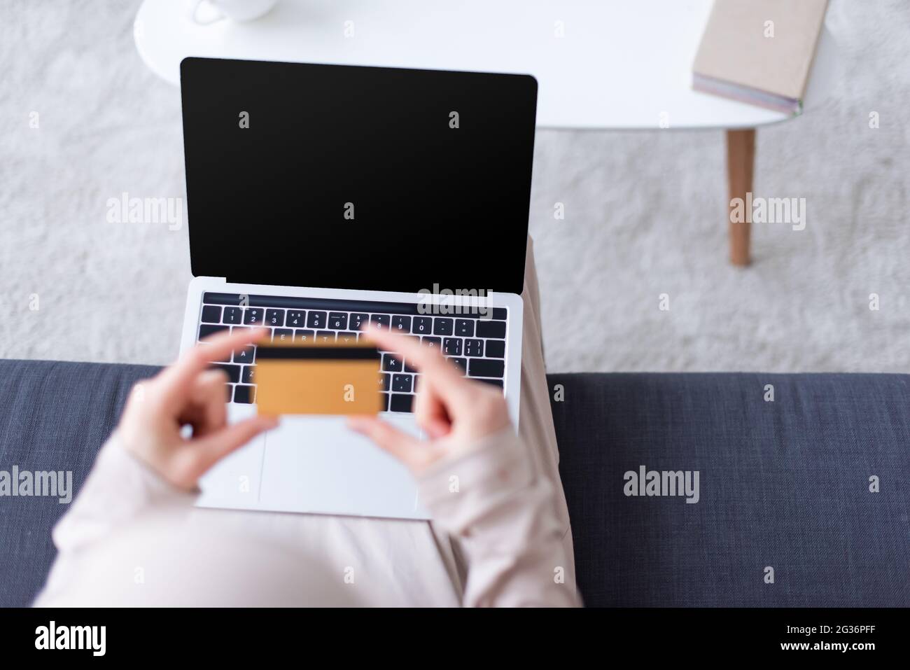 overhead view of muslim woman holding credit card near laptop with ...