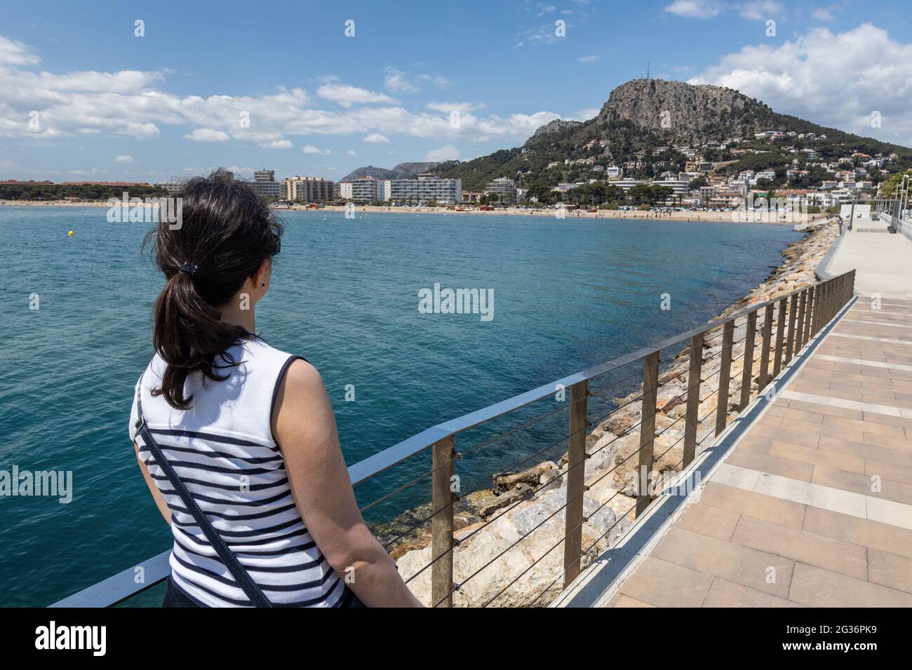Pretty Spanish tourist woman looking at seascape from small town L ...