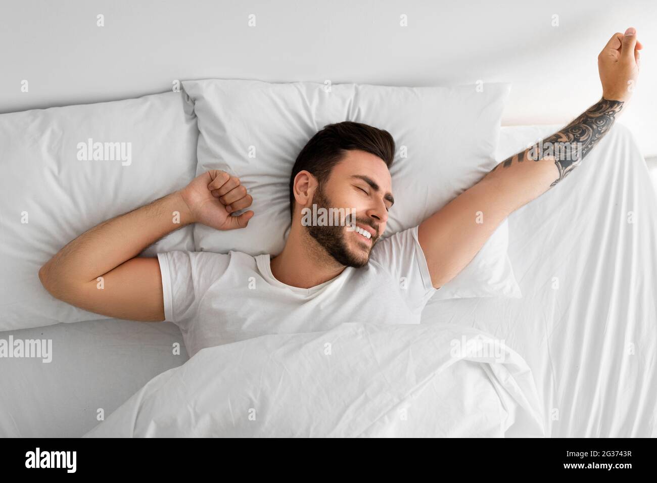 Awakening concept. Happy rested wellslept man waking up in morning and ...