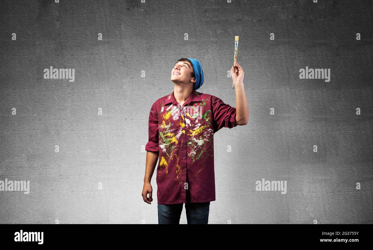 Smiling young painter artist pointing upwards Stock Photo - Alamy