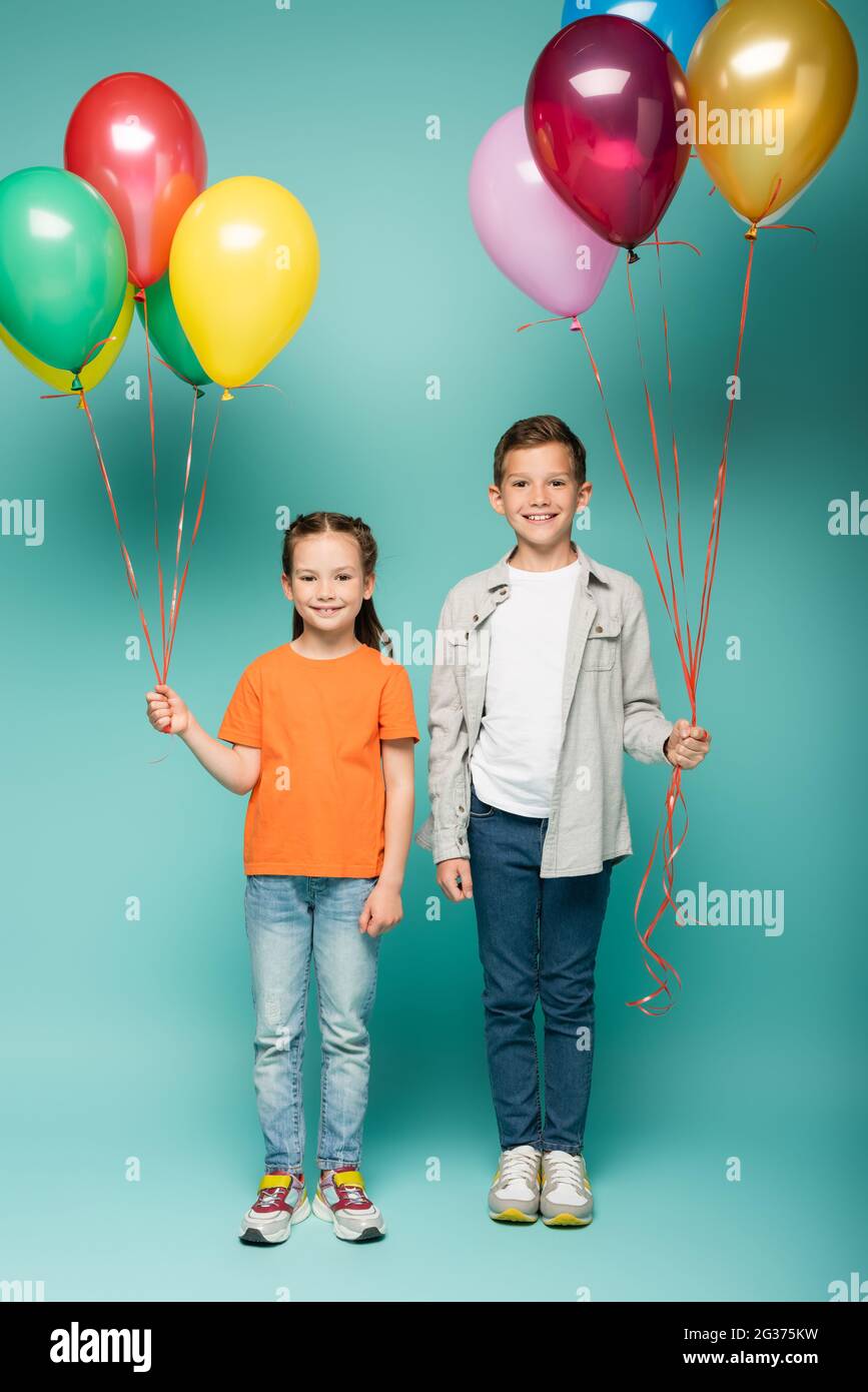 happy children holding colorful balloons on blue Stock Photo - Alamy