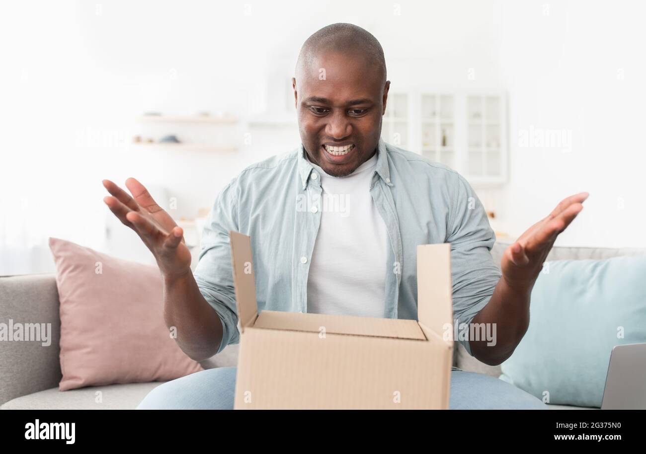Angry african american mature man checking mail box, sitting on sofa at ...