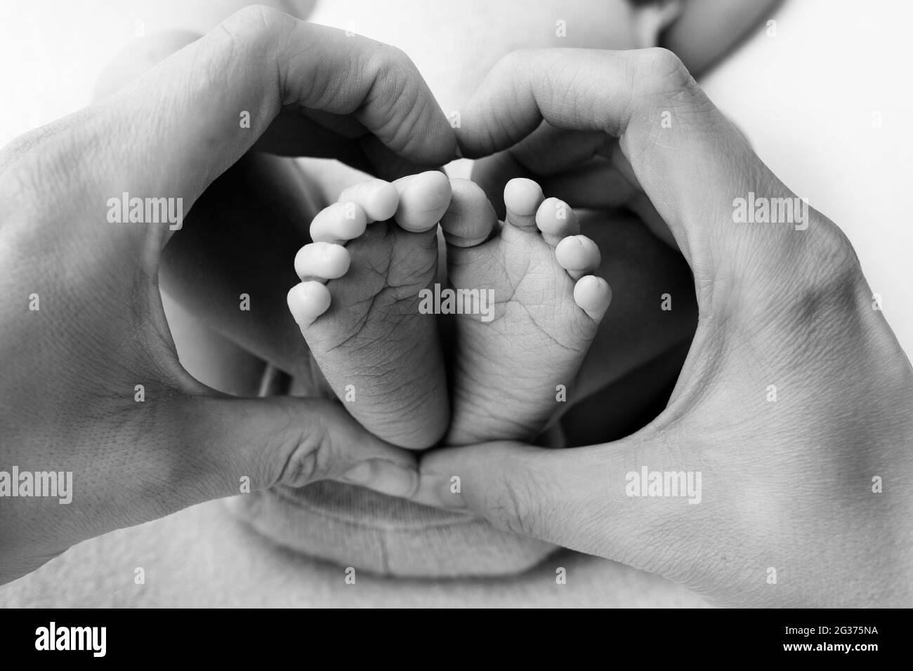 A parent's hands in the shape of a heart around a newborn baby's feet ...
