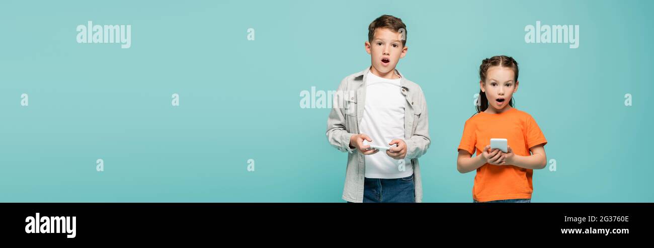 shocked children holding cellphones and looking at camera isolated on ...