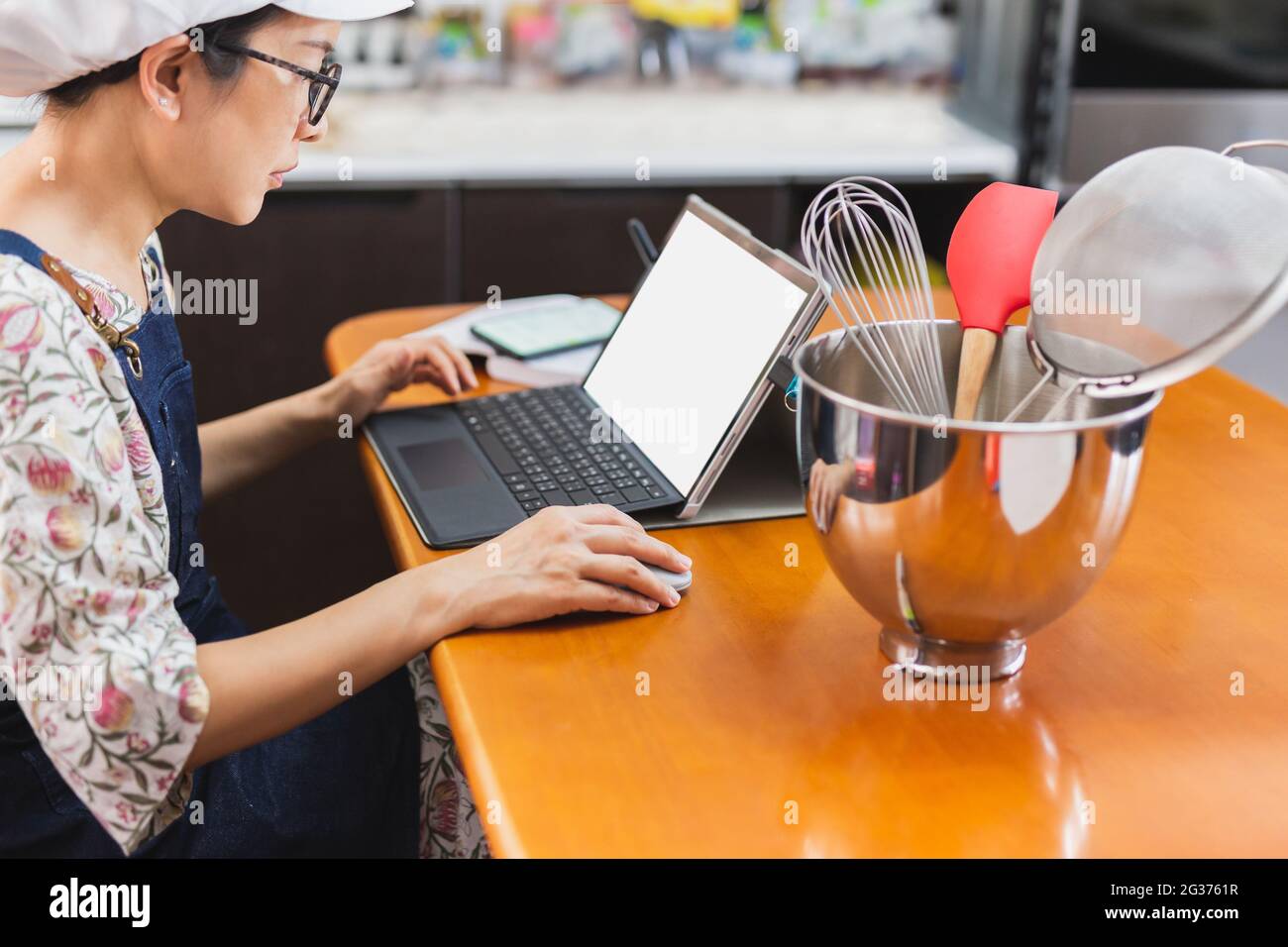Businesswoman baker working on with laptop bakery equipment on table ...