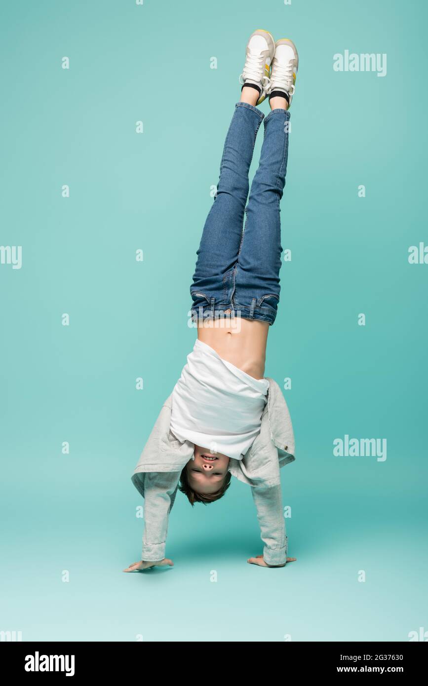 happy boy in denim jeans doing handstand on blue Stock Photo - Alamy