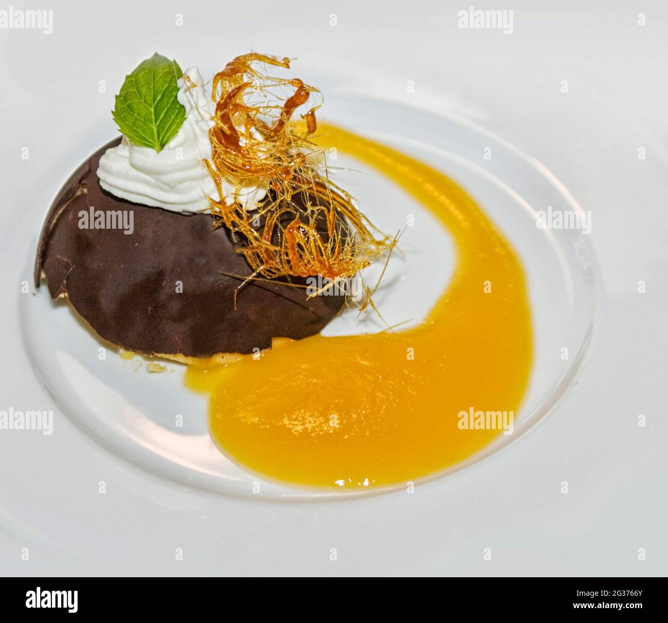 Beautiful chocolate bombe with mangomousse and sauce Stock Photo - Alamy