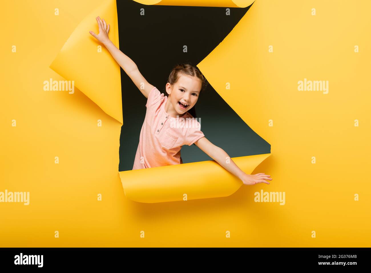 excited kid with outstretched hands looking at camera through ripped ...