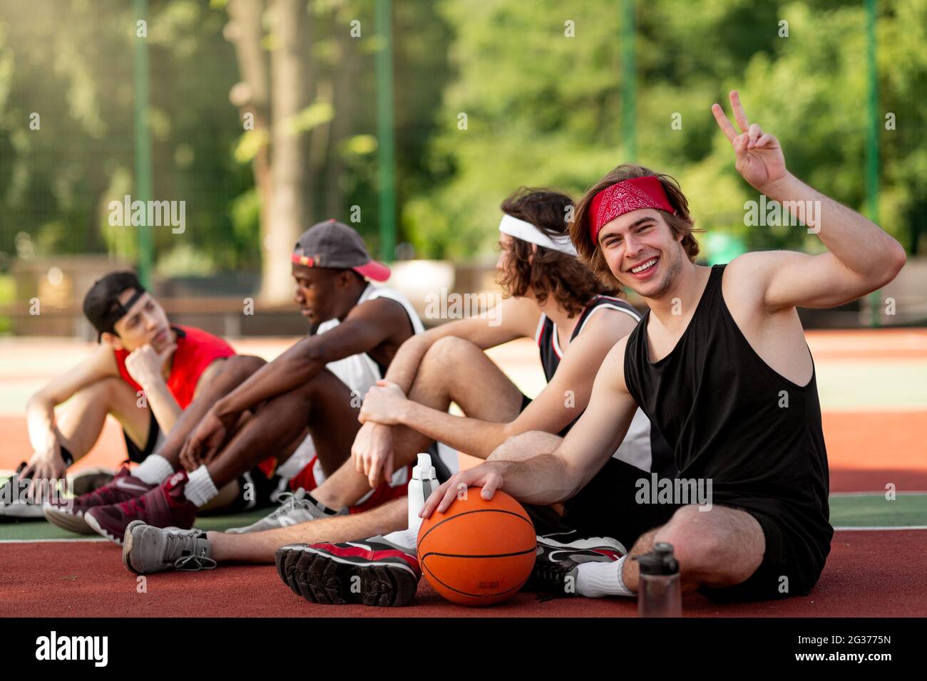 Happy young basketball player and his multinational team having rest at ...