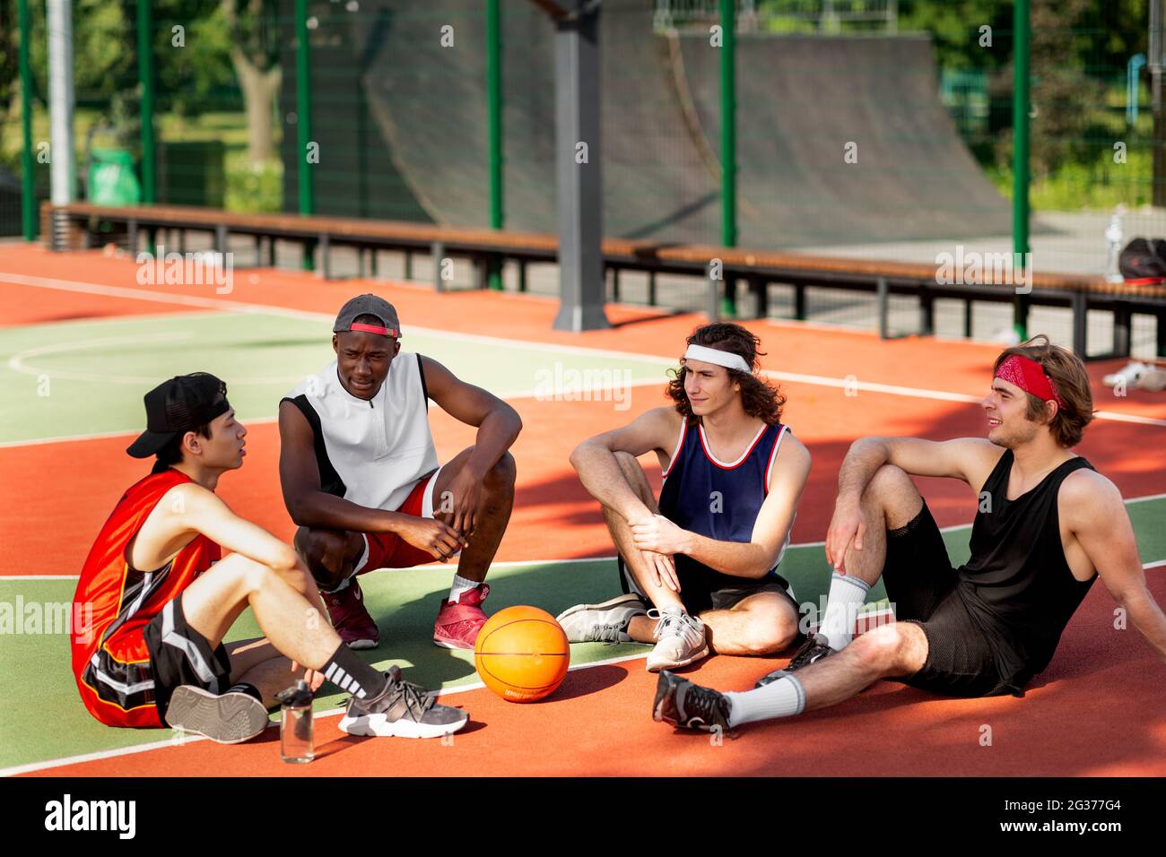 Diverse team of basketball players getting some rest after game at ...