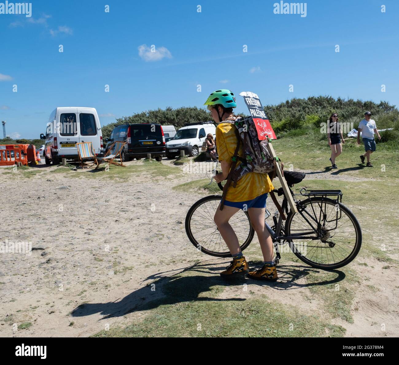 Young protestor leaving the protest at Hayle pushing a bike through the ...