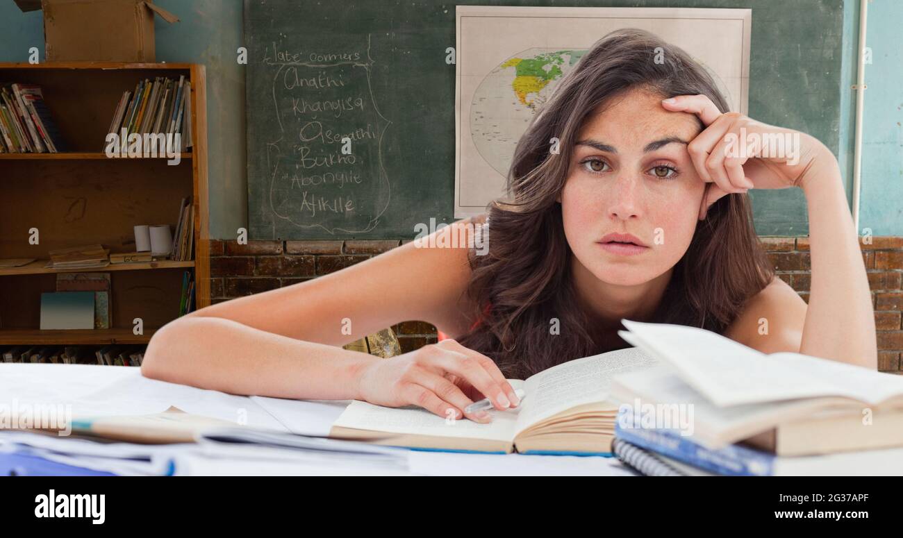 Composition of stressed female teacher leaning on desk with books and a ...