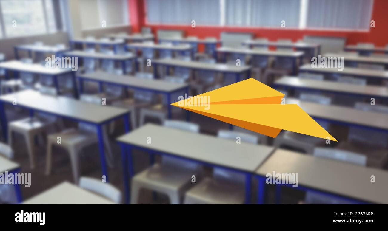 Composition of yellow paper aeroplane flying over desks in empty ...