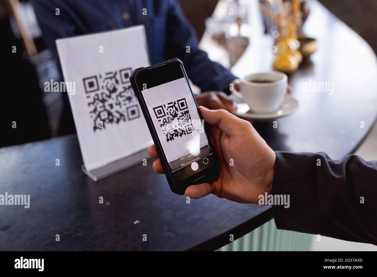 Mid section of man making a payment by scanning qr code from smartphone ...