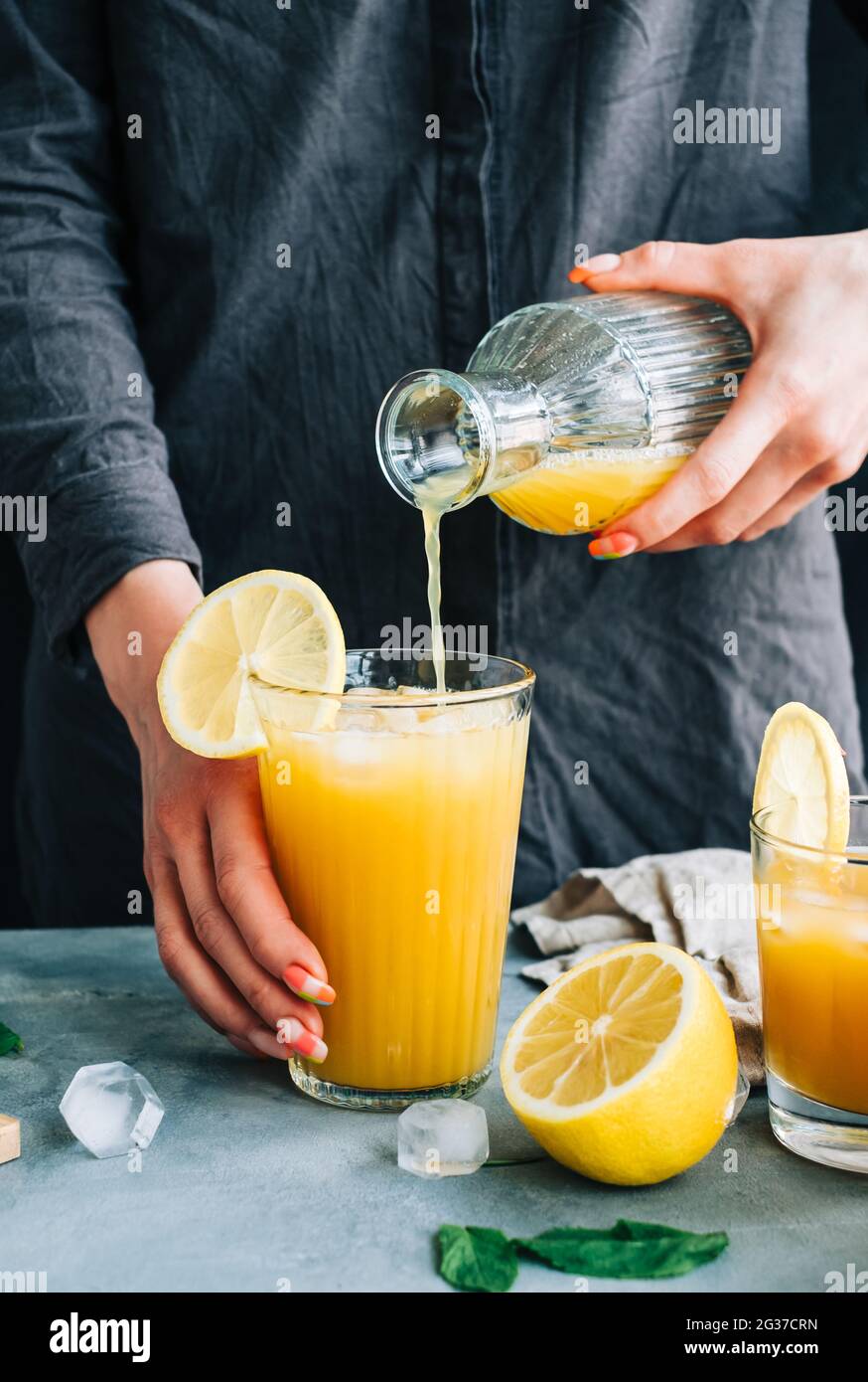 Female bartender pours fresh lemonade from bootle in glass with ice ...