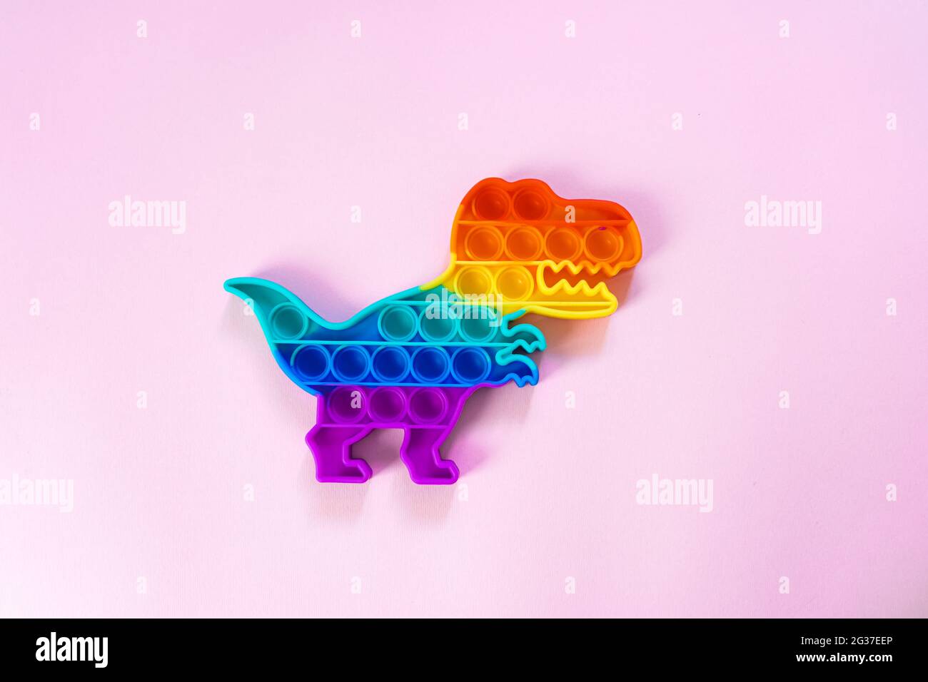 Popit rainbow toy in rainbow colours and dino shape. Trendy bubble pop ...