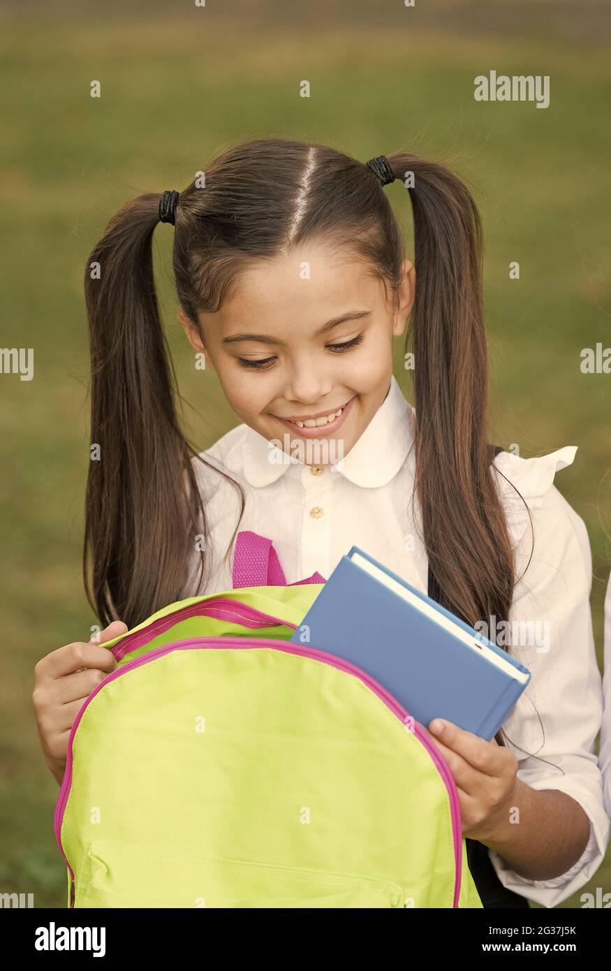 Schoolgirl putting book inside backpack, ready for lessons concept ...