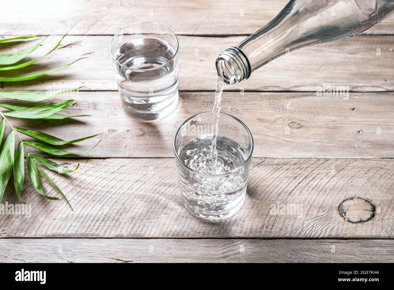 Water pouring into glass. Glass of water on wooden table, selective focus, close up. Clear ...