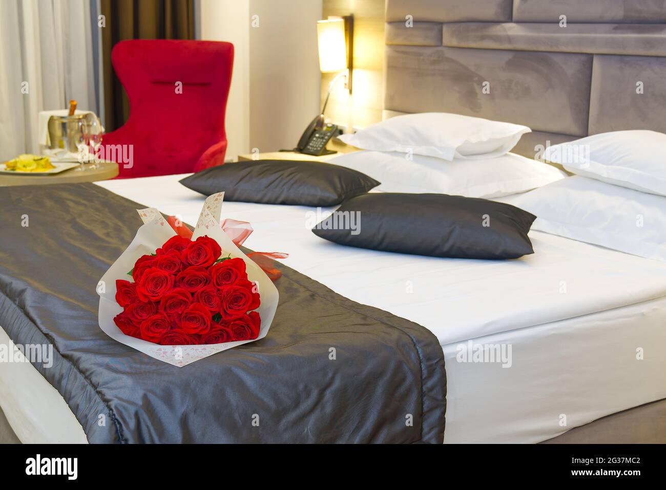 bouquet of red roses on the bed in a hotel room for honeymoon. romantic ...