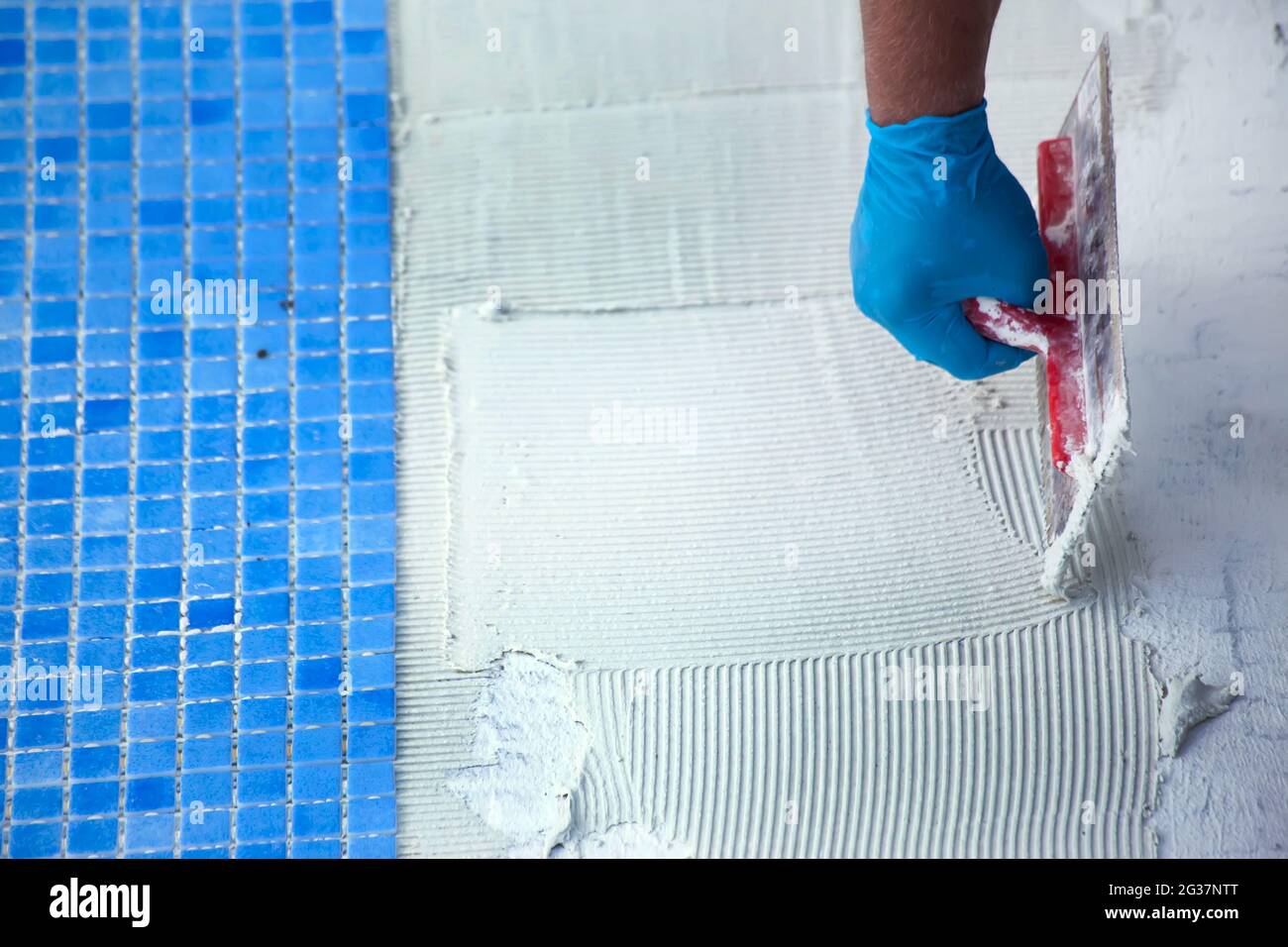 Worker laying tile in the pool. Pool repairing work Stock Photo - Alamy