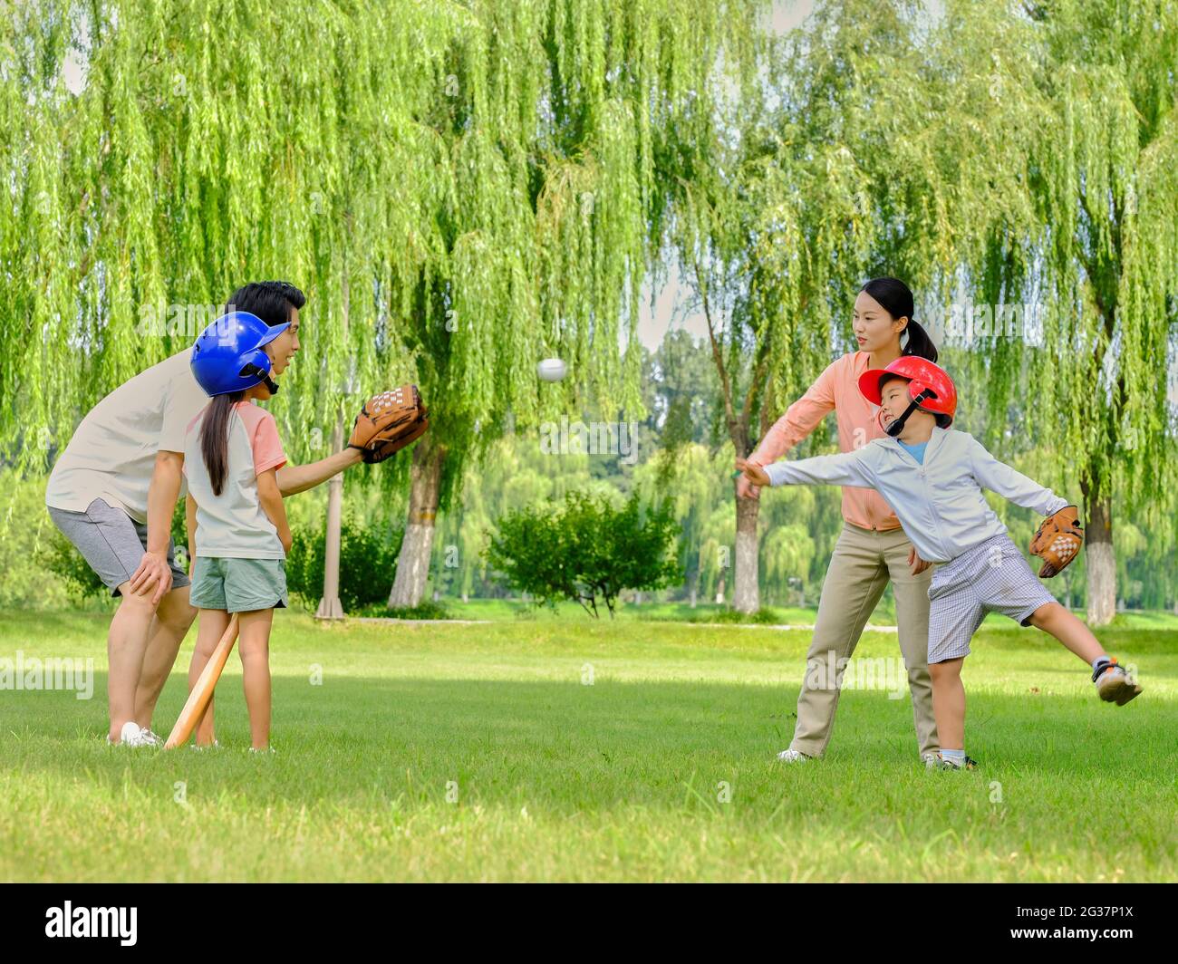 Happy family of four playing baseball in the park high quality photo ...