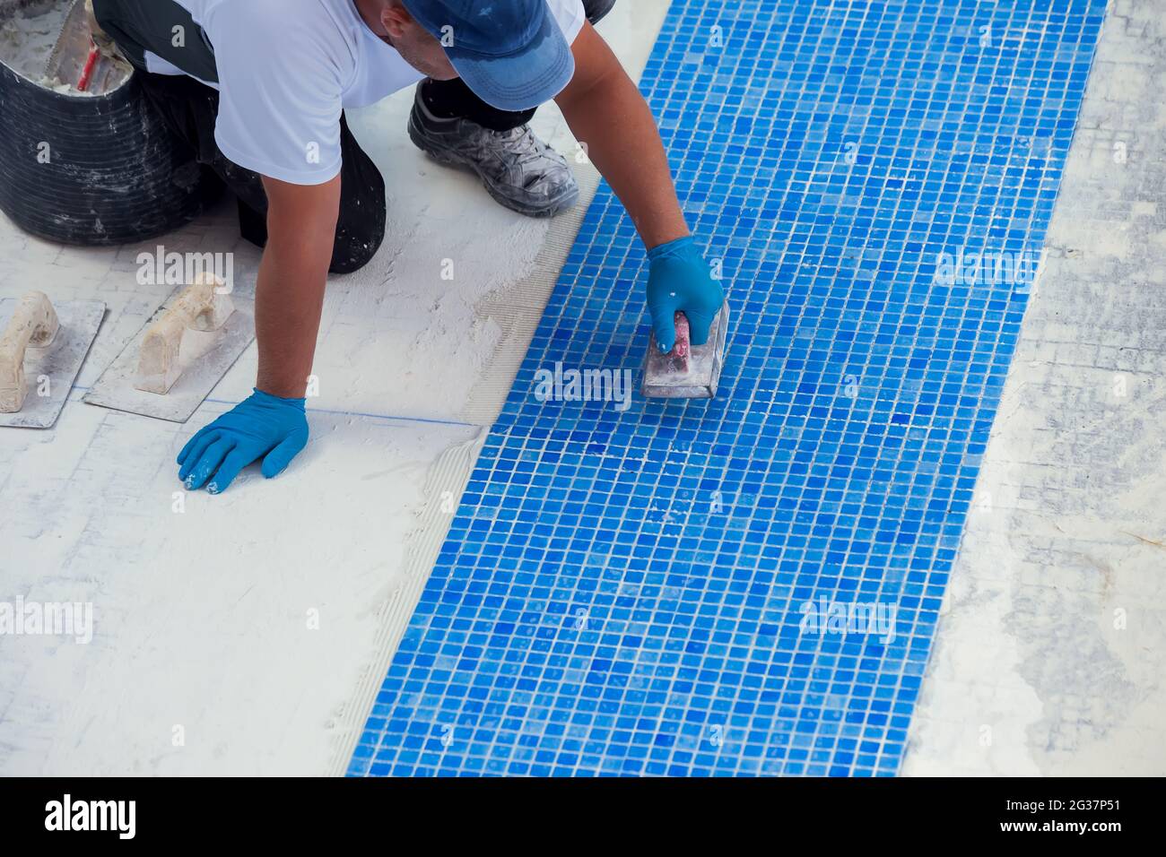 Worker laying tile in the pool. Pool repairing work Stock Photo - Alamy