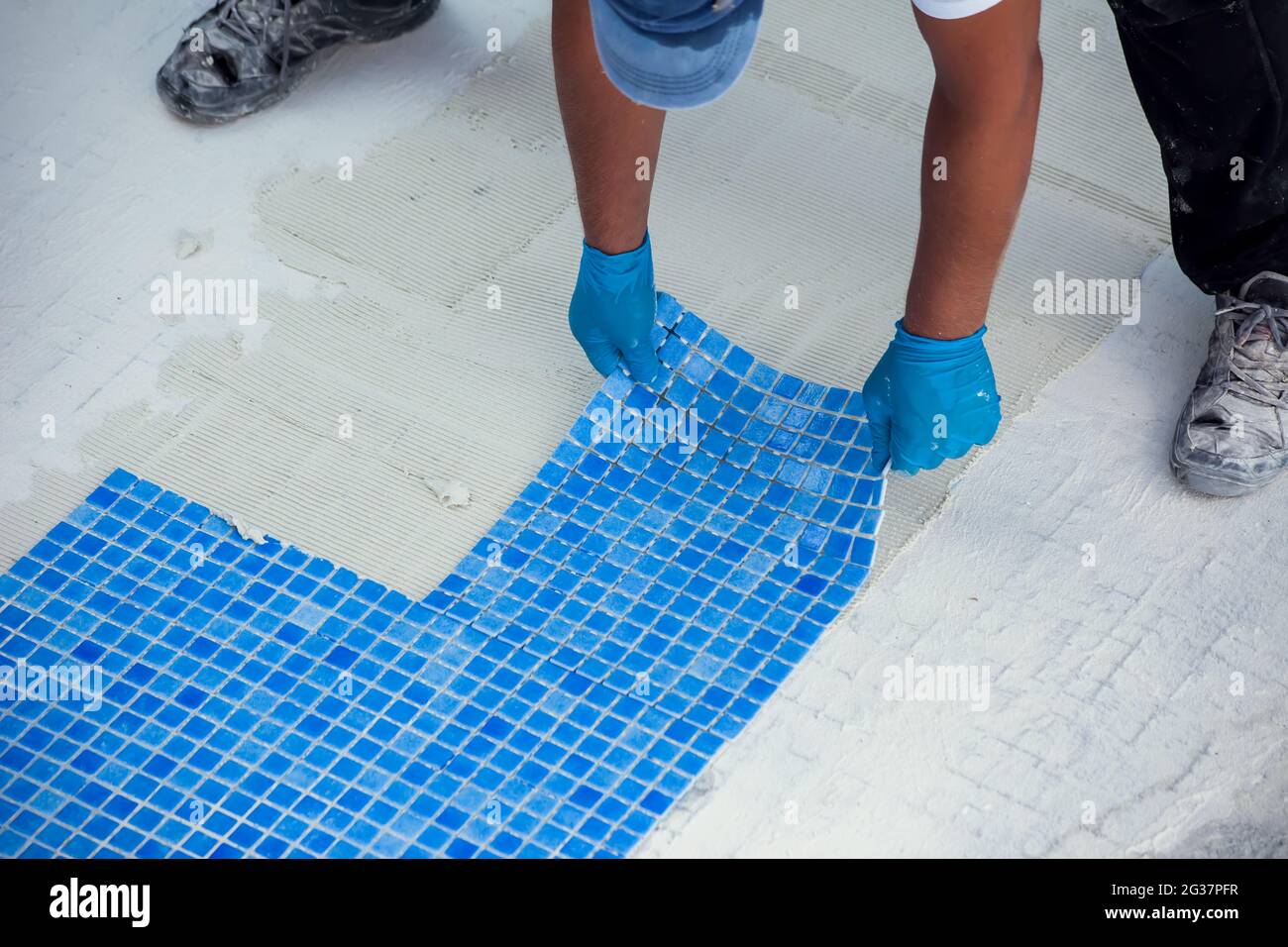 Worker laying tile in the pool. Pool repairing work Stock Photo - Alamy