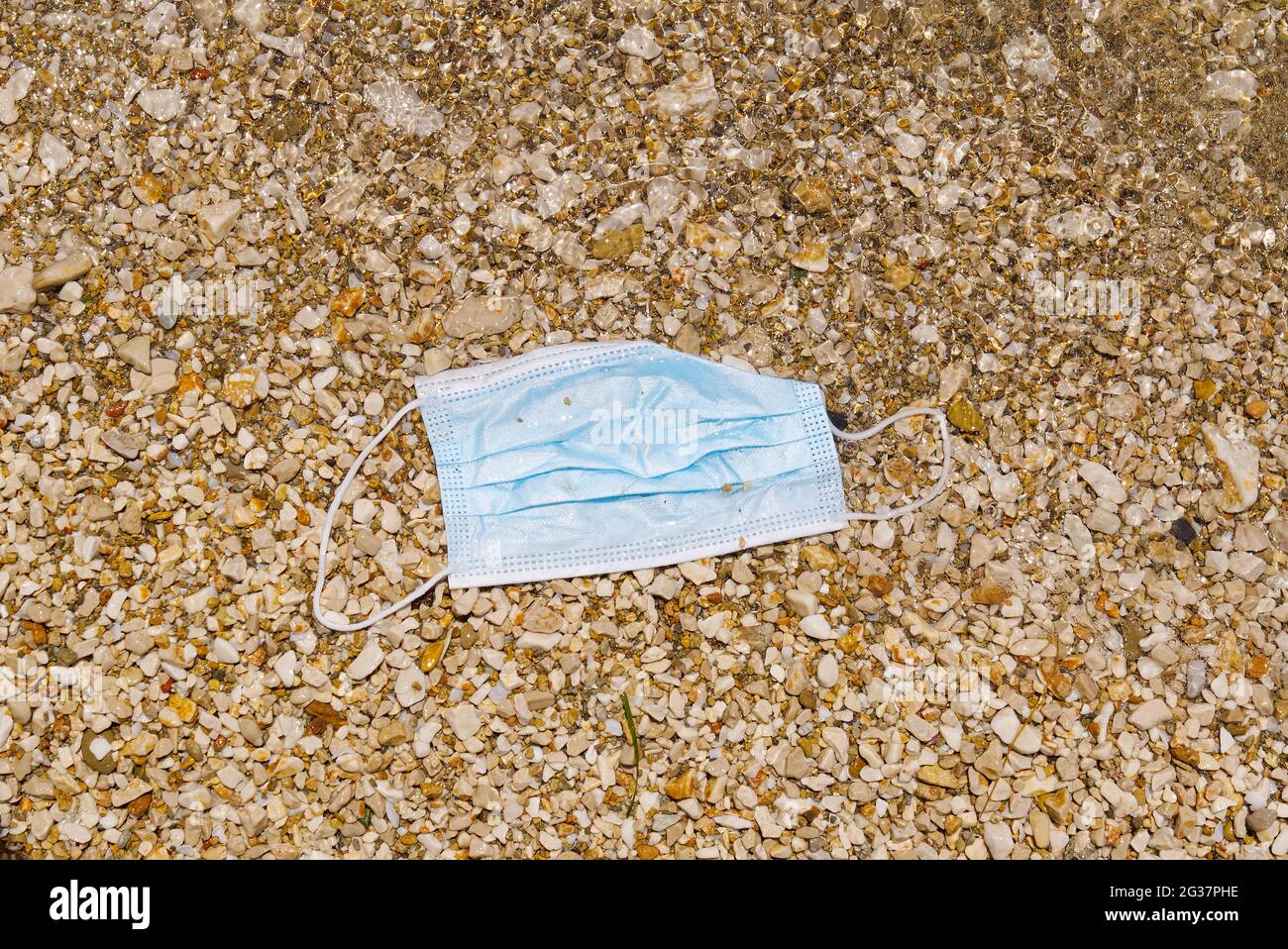 Used blue medical face mask lies on the beach. Environmental and coast ...